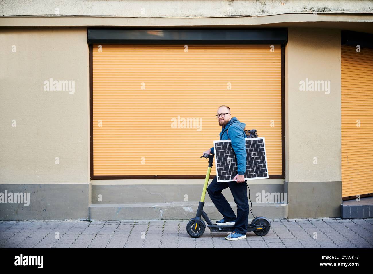Man rides electric scooter while carrying solar panel. Integration of ...
