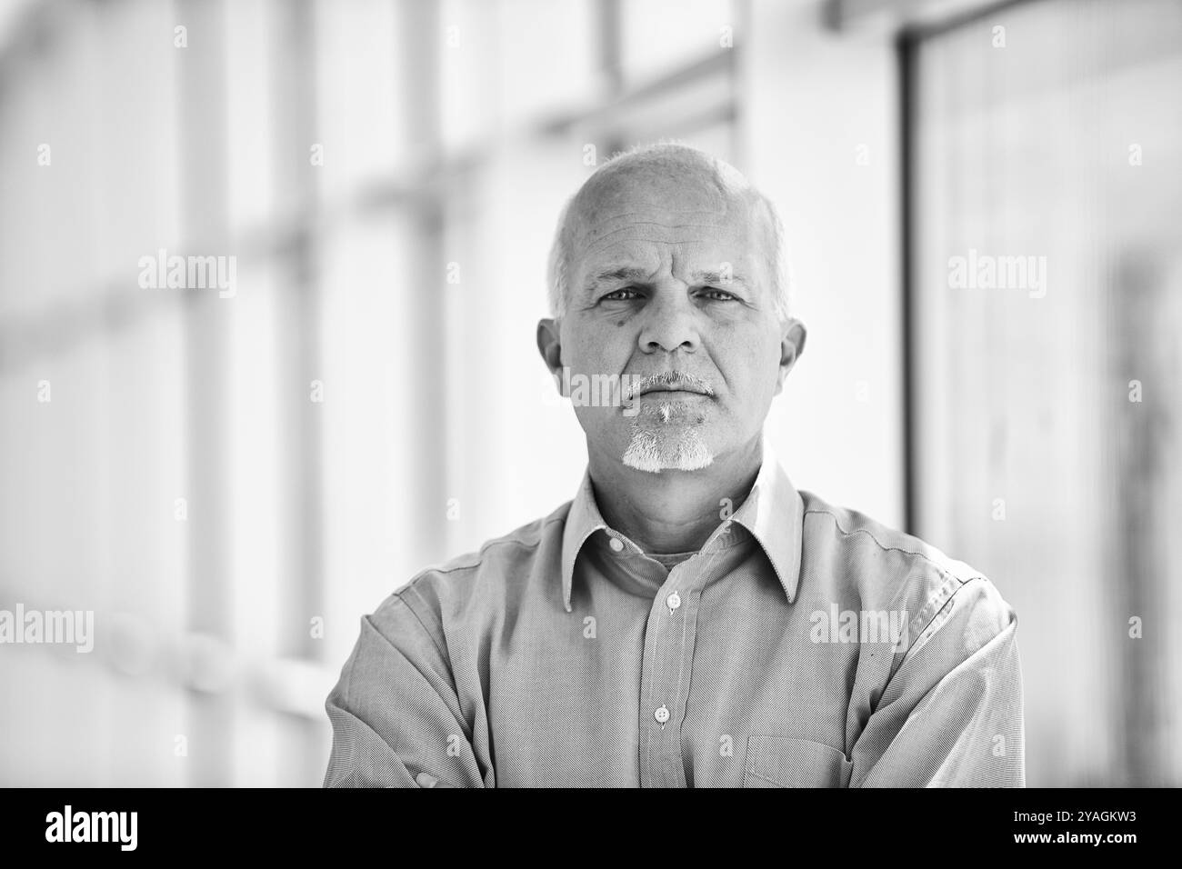 Confident senior engineer with arms crossed in modern office, exuding ...