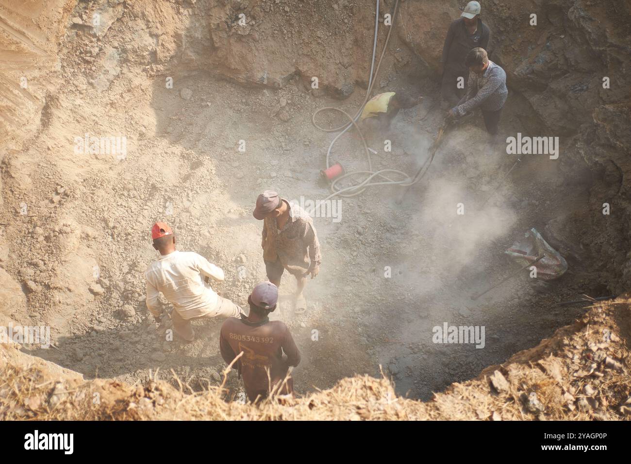 Well diggers digging inside a well through layers of stone and earth ...
