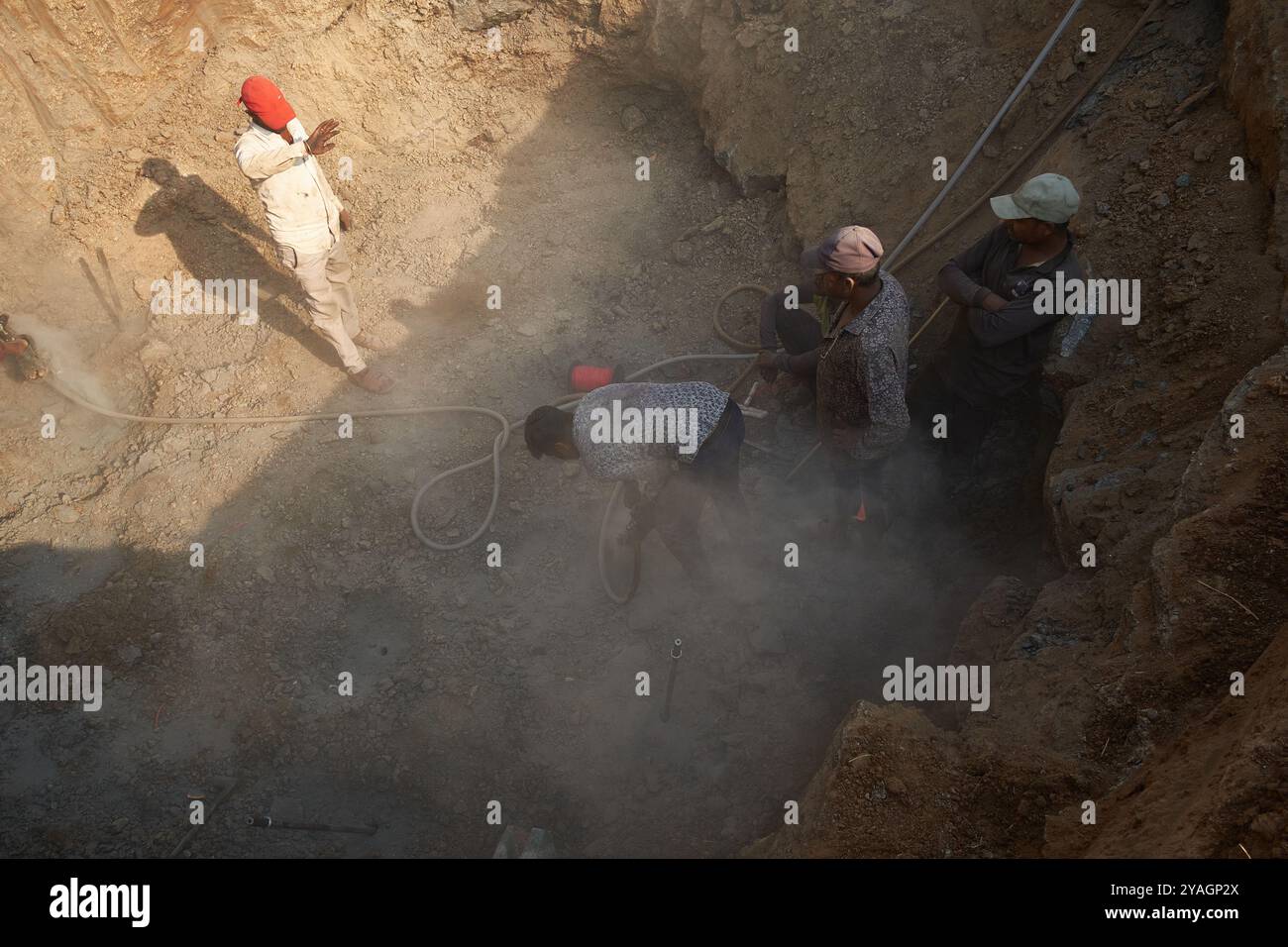 Well diggers use pneumatic drills to make holes in stones where they ...
