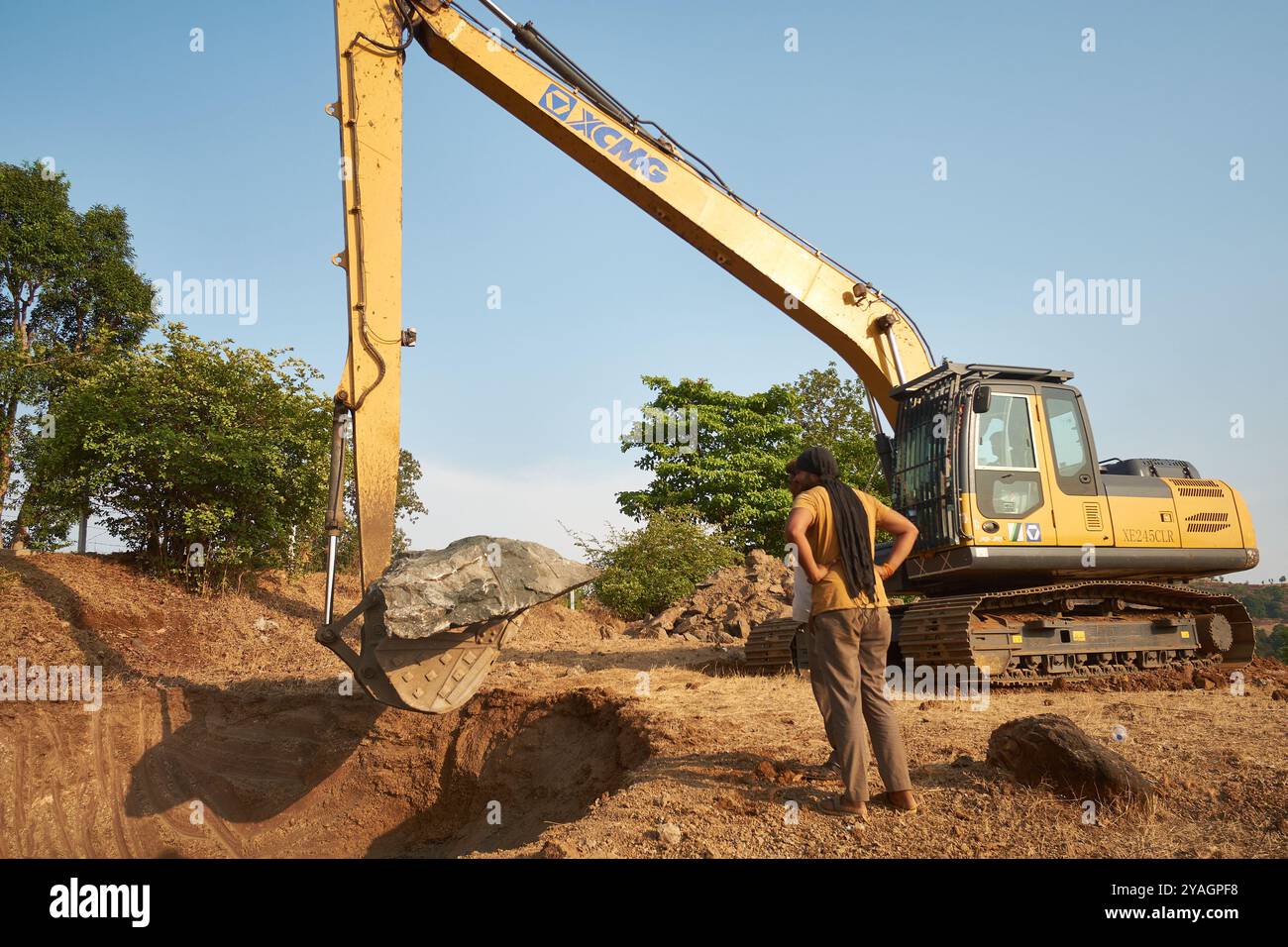 Men working with a heavy excavating machine to dig a well in the dry ...