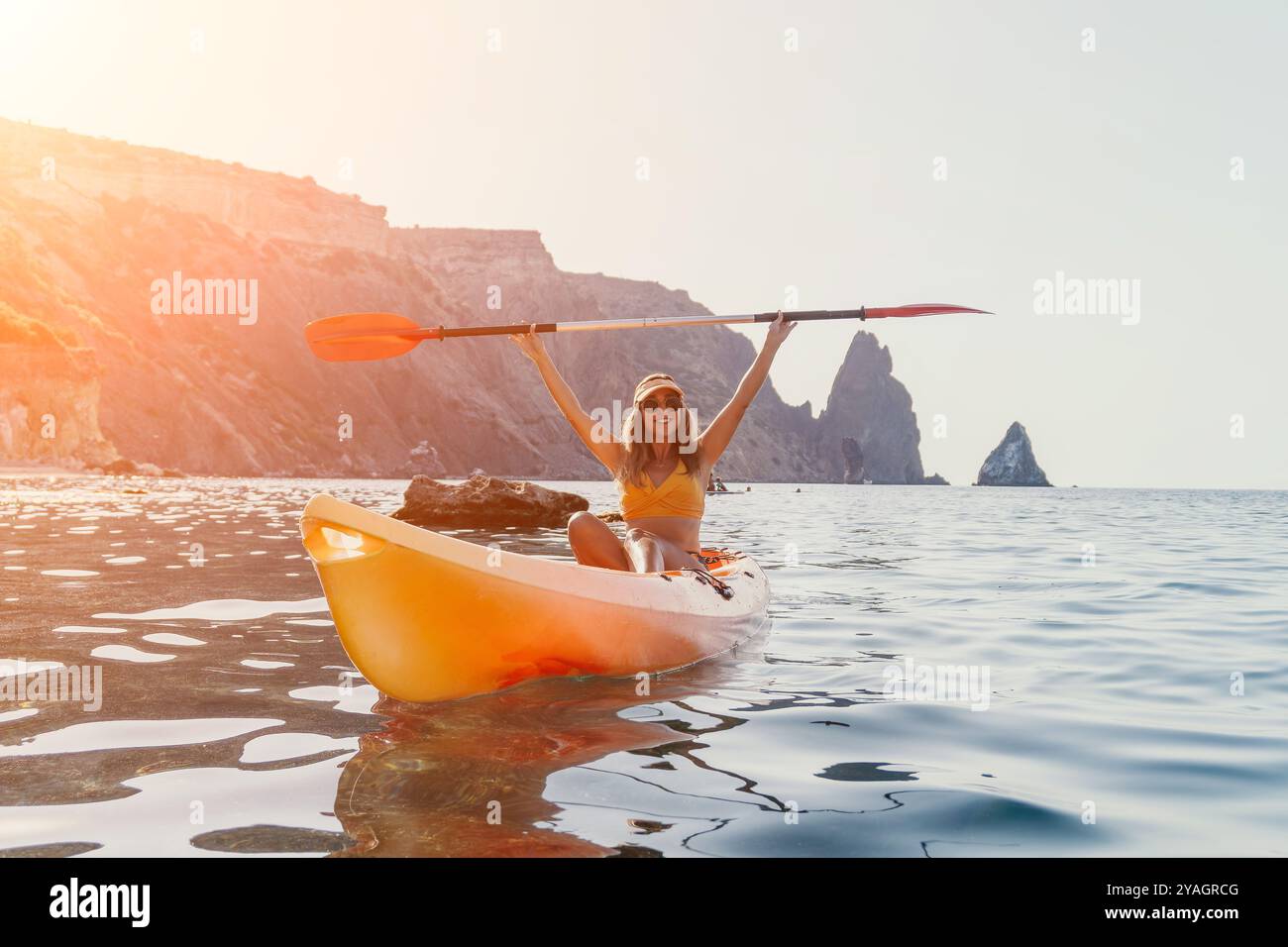 Woman Kayaking Ocean - Woman enjoys kayaking in the ocean with cliffs ...