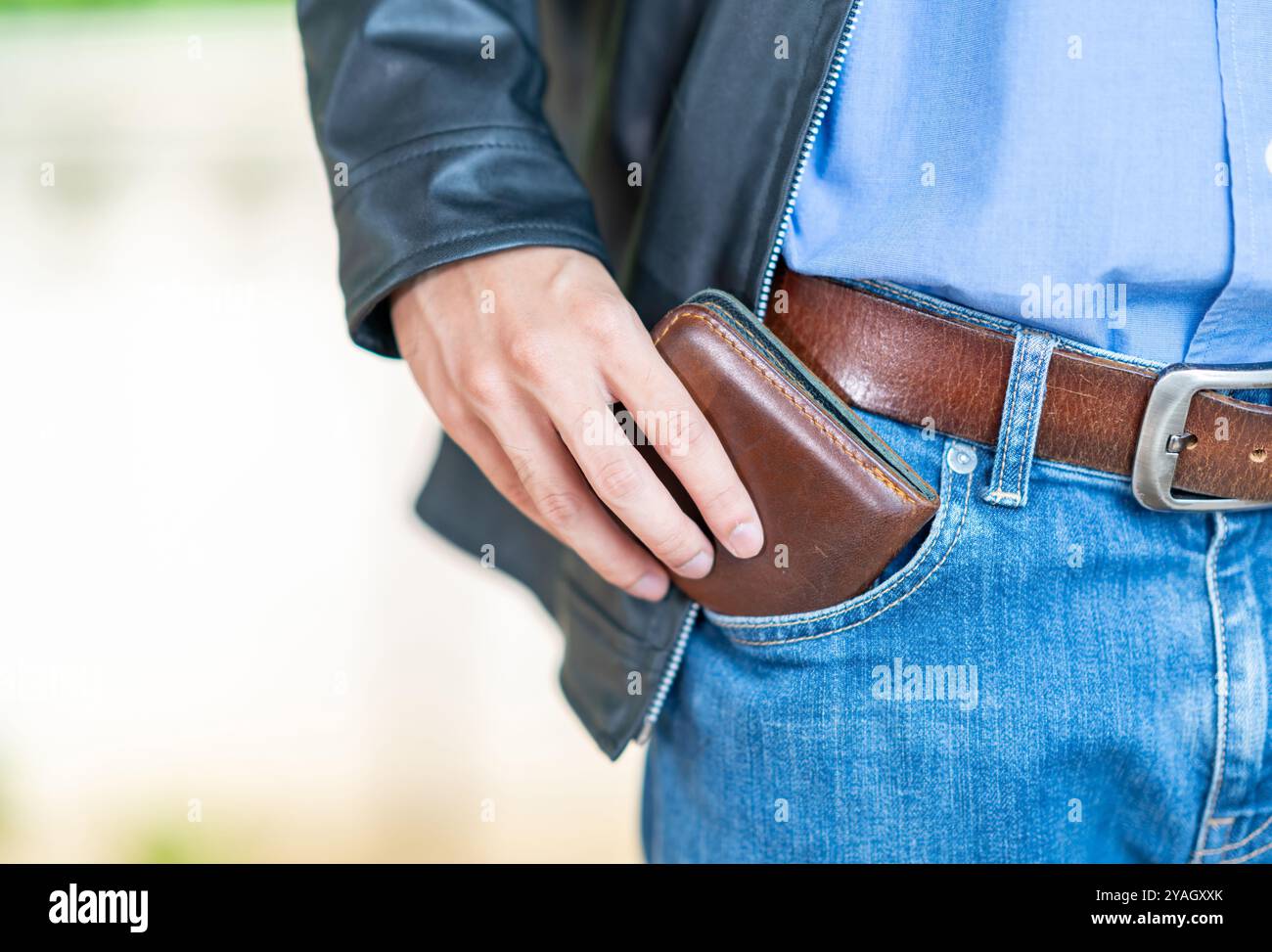 The man in leather jacket pulls a brown leather wallet on jeans pocket ...