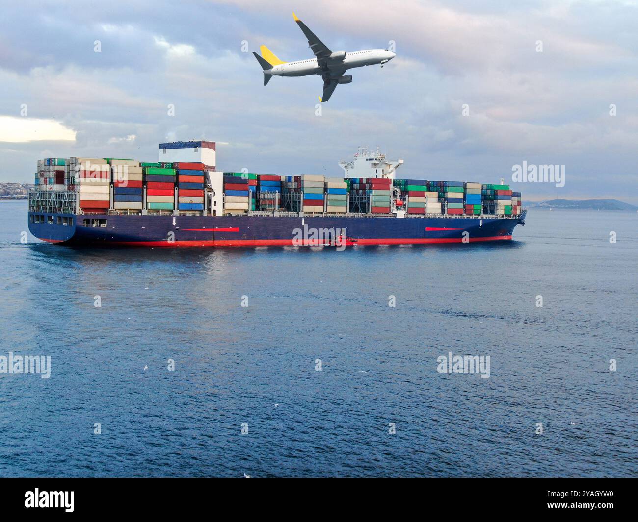 A large cargo ship is sailing in the ocean with a plane flying above it ...