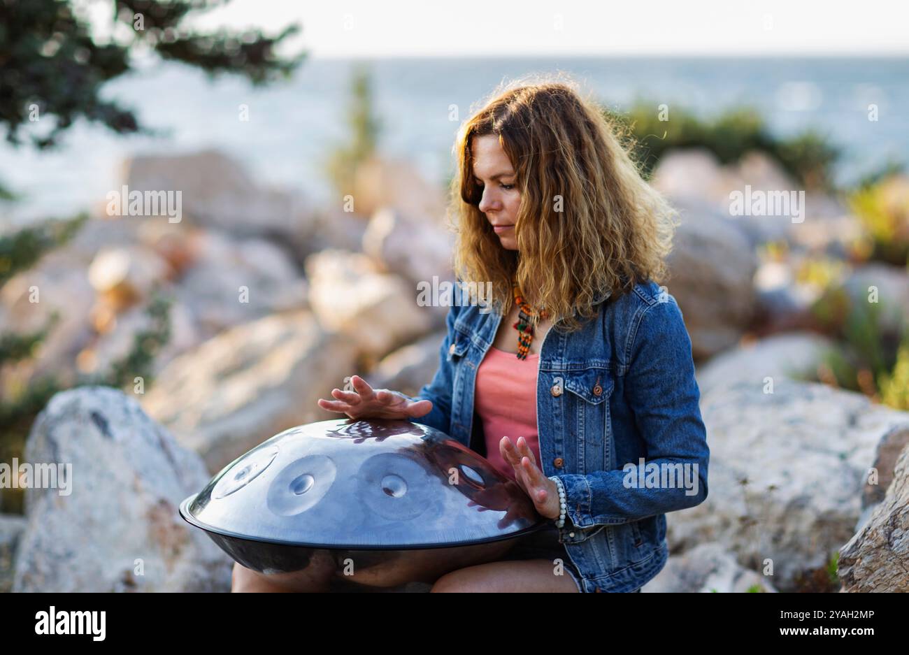Attractive young woman playing handpan drum on the stone Stock Photo ...