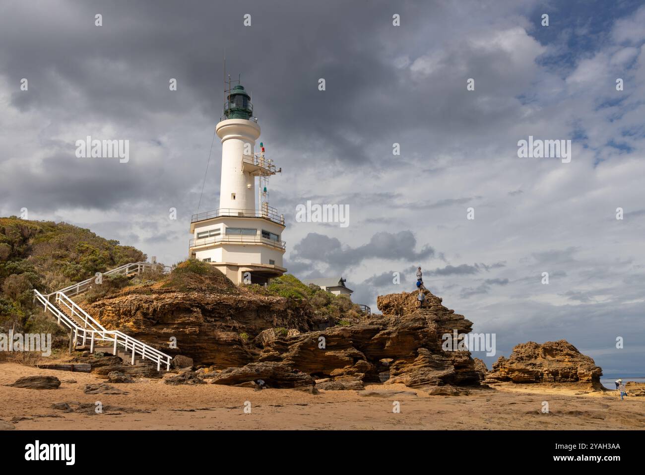Point Lonsdale Lighthouse atop rocky cliff under dramatic cloudy sky ...