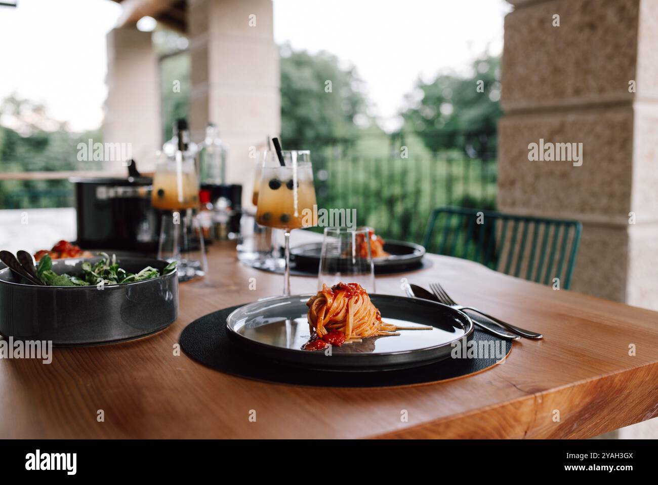 Outdoor dining with pasta and drinks on a wooden table setting Stock ...