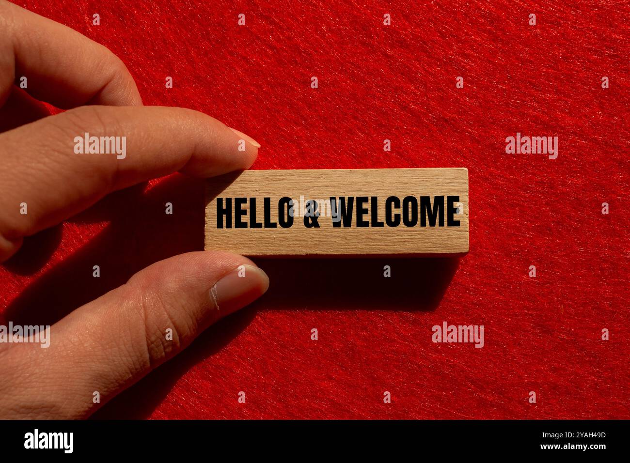 Hello and welcome message written on wooden block with red background ...
