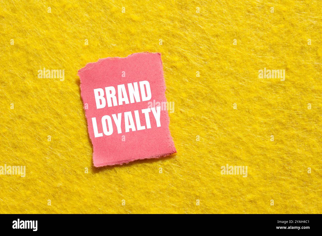 Brand loyalty message written on ripped pink torn paper piece with ...