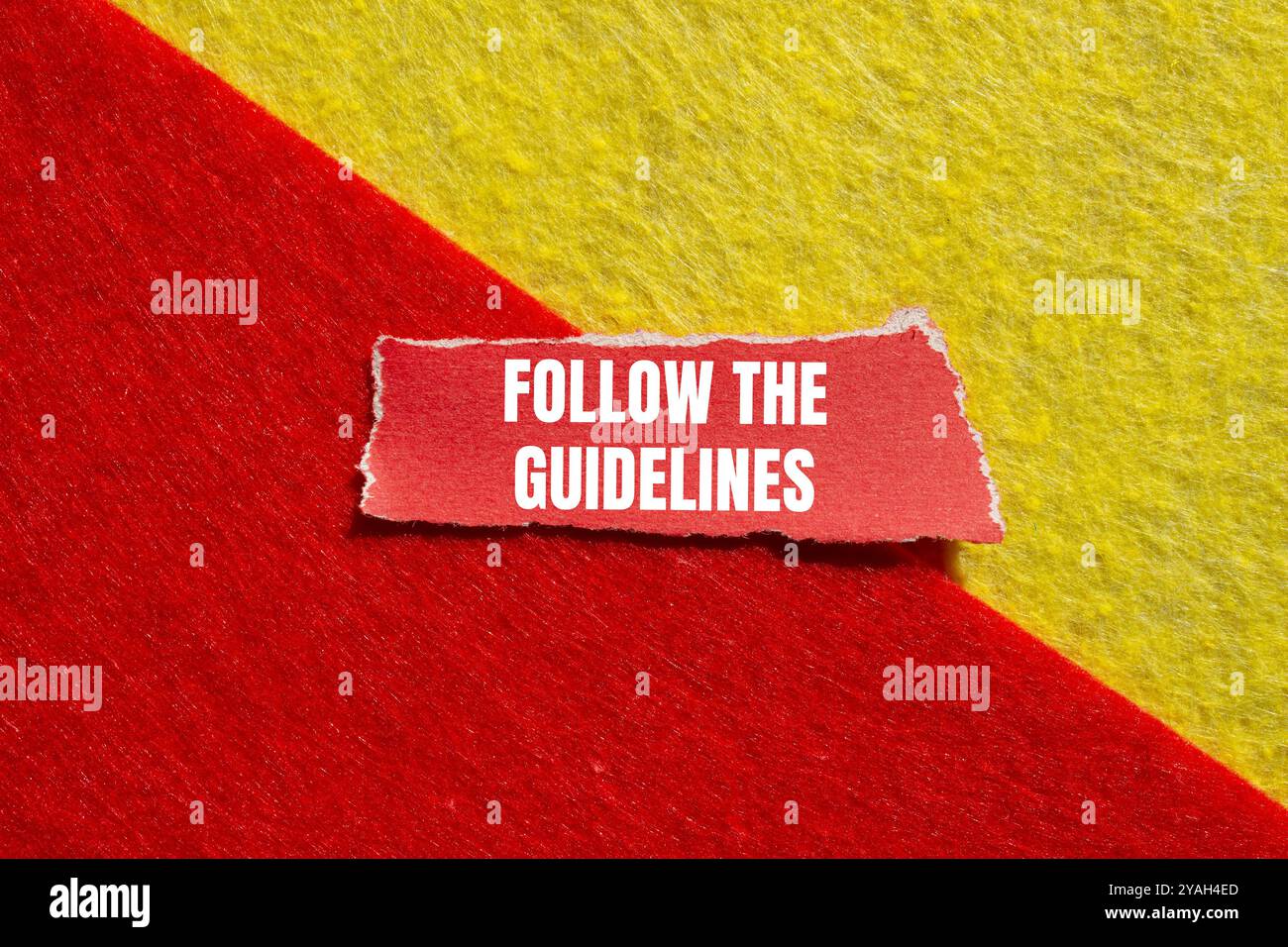 Follow the guidelines message written on ripped torn red paper piece with yellow red background ...