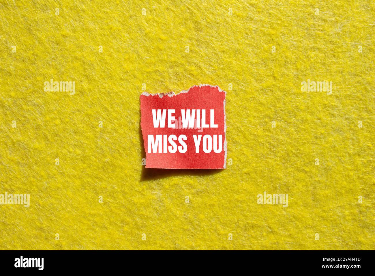 We will miss you message written on ripped torn red paper piece with yellow background ...