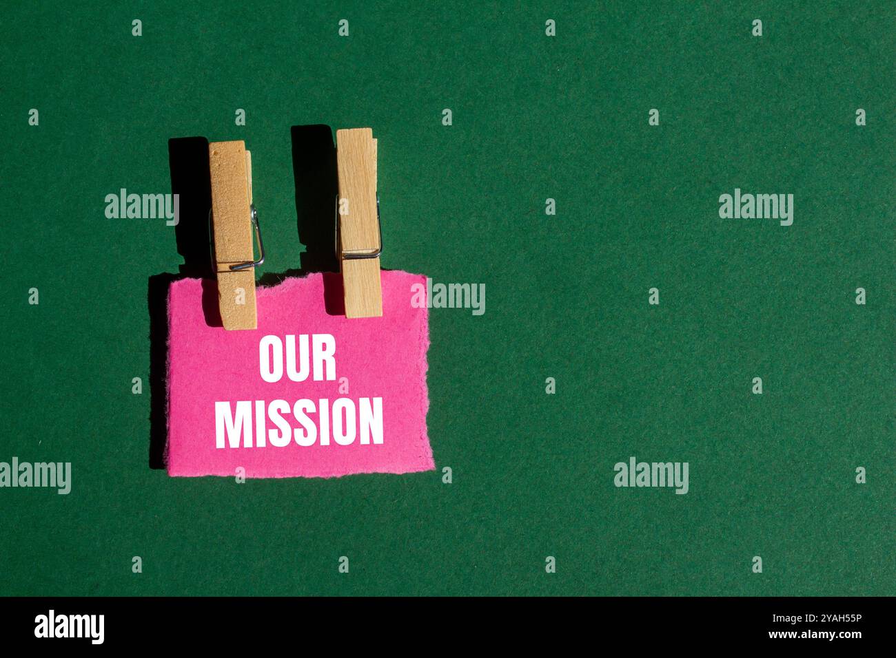 Our mission message written on ripped torn pink paper piece with green ...