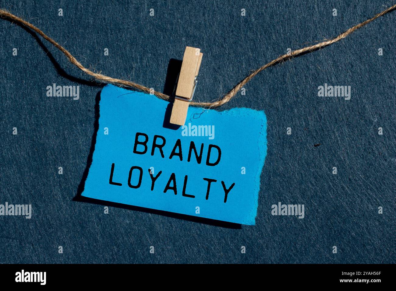 Brand loyalty message written on ripped blue torn paper piece with gray ...