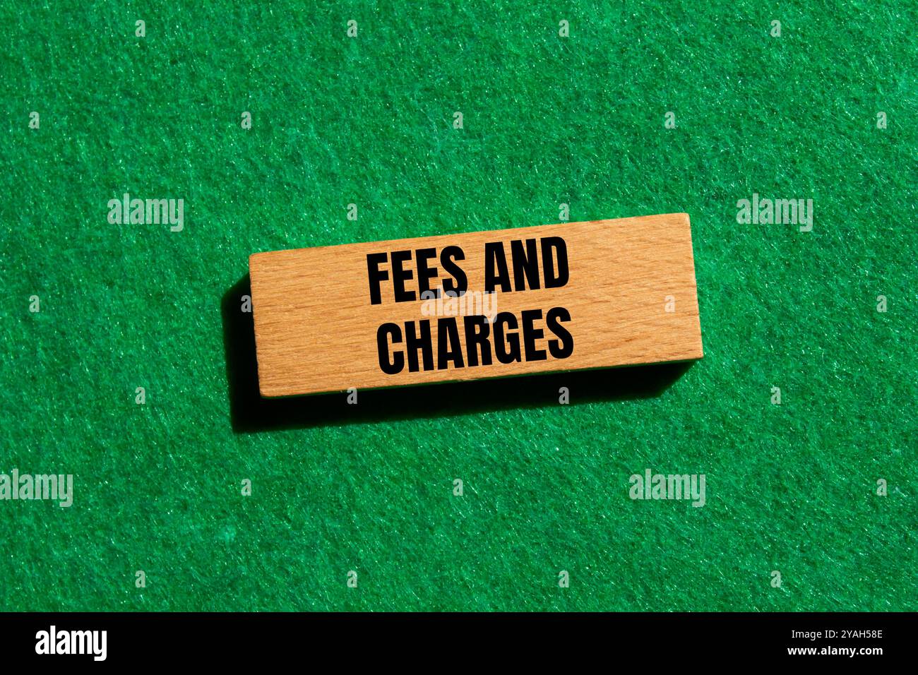 Fees and charges message written on wooden block with green background ...