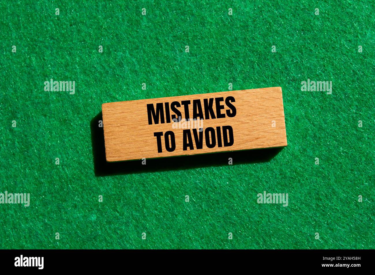 Mistakes to avoid message written on wooden block with green background ...