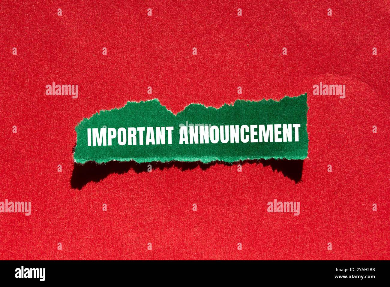 Important announcement message written on ripped torn green paper piece with red background ...