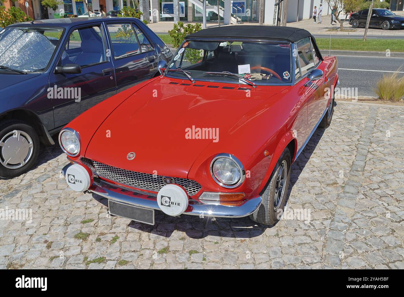 Classic red fiat 124 sport spider parked in a parking lot with a modern ...