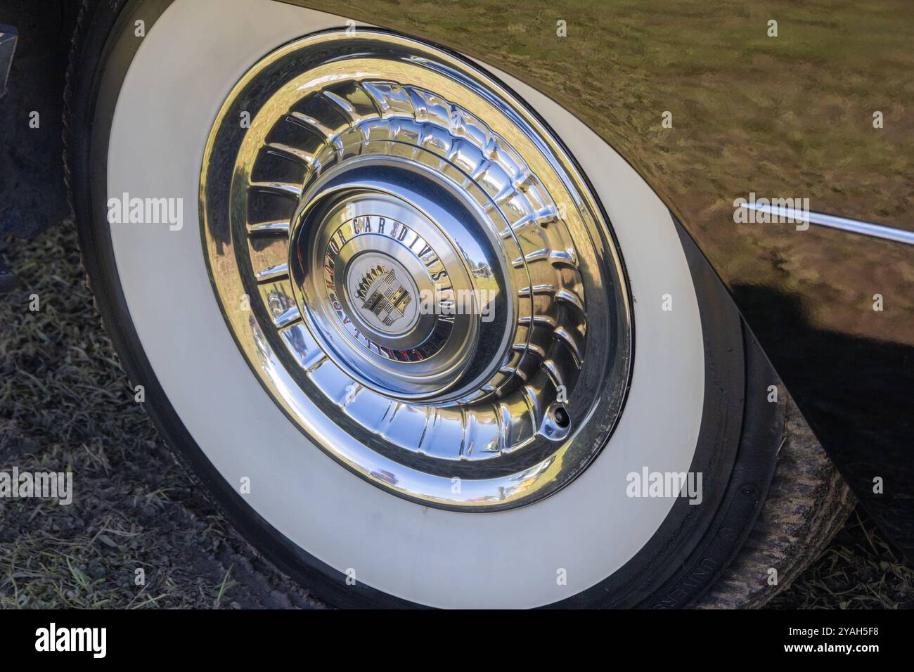 Shining chrome hubcap on a whitewall tire of a vintage cadillac coupe ...