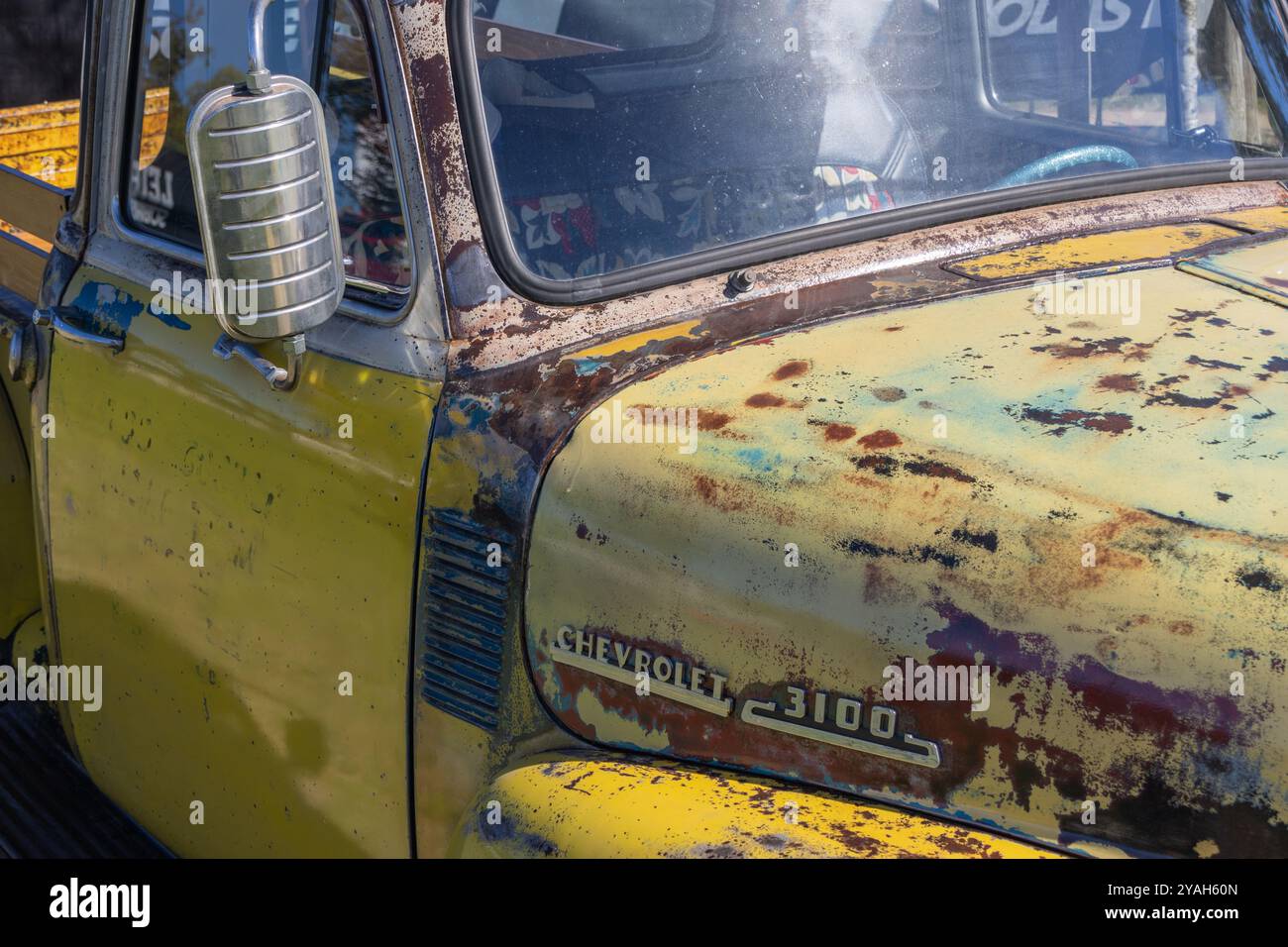 Showing its age and wear, the rusty yellow paint of a vintage chevrolet ...
