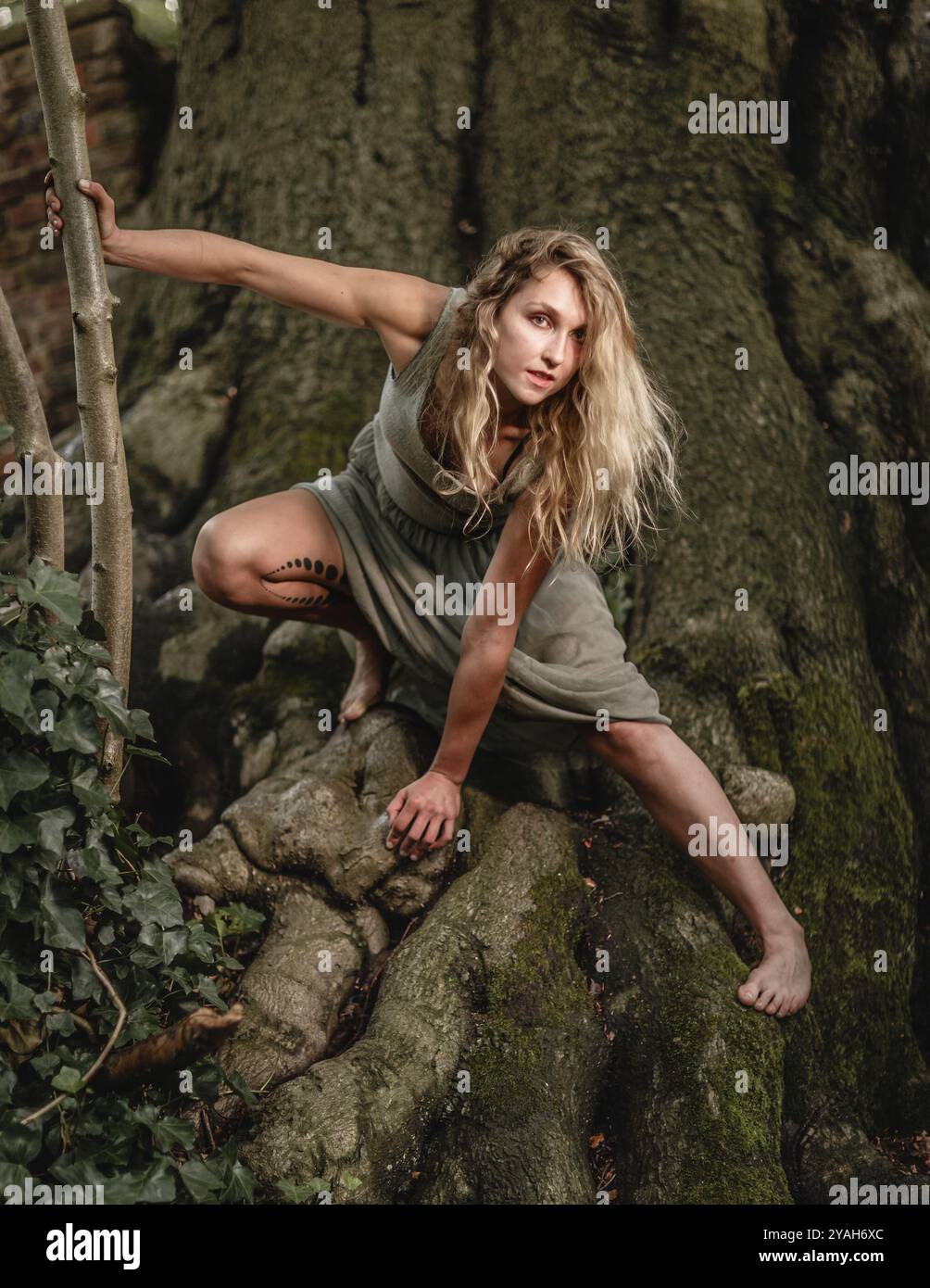 A feral model poses on a tree in London Stock Photo - Alamy