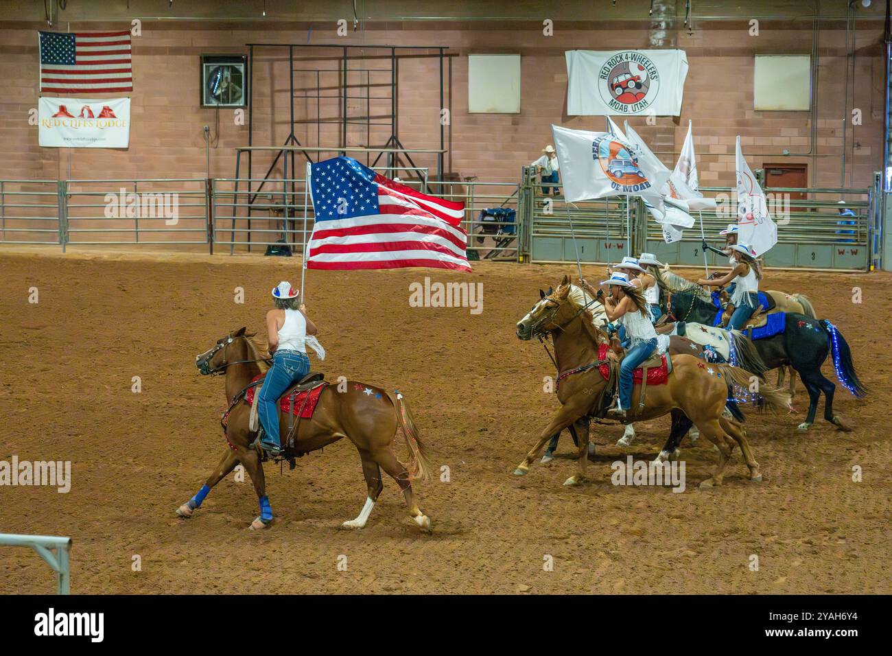 Cowgirls in a mounted drill team perform with flags at the beginning of ...