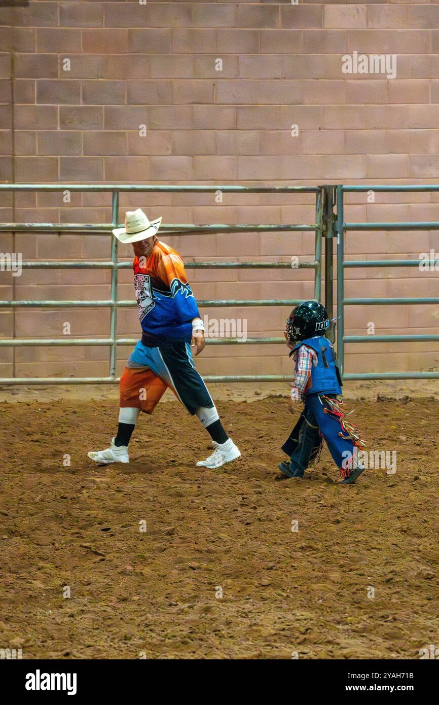 A young cowboy follows a rodeo clown after riding a bucking pony at the ...