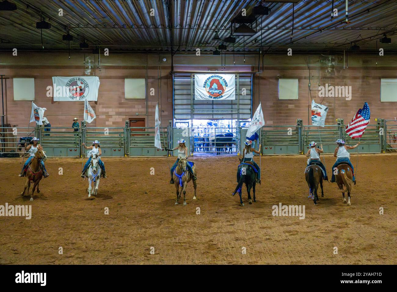 Cowgirls in a mounted drill team perform with flags at the beginning of ...