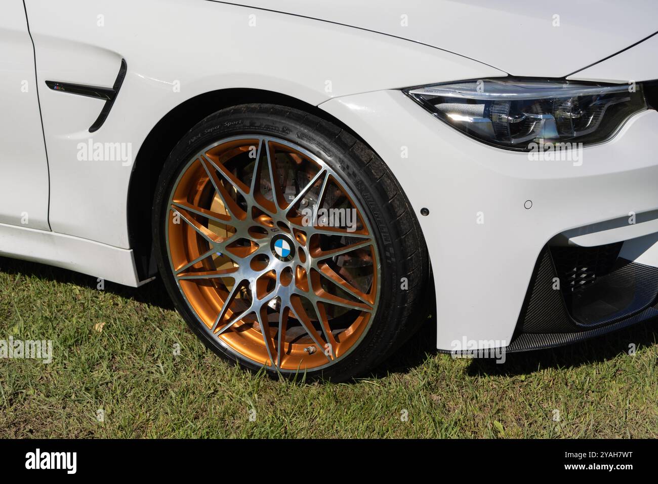 Close up of a copper and silver alloy wheel of a white bmw m4 parked on ...