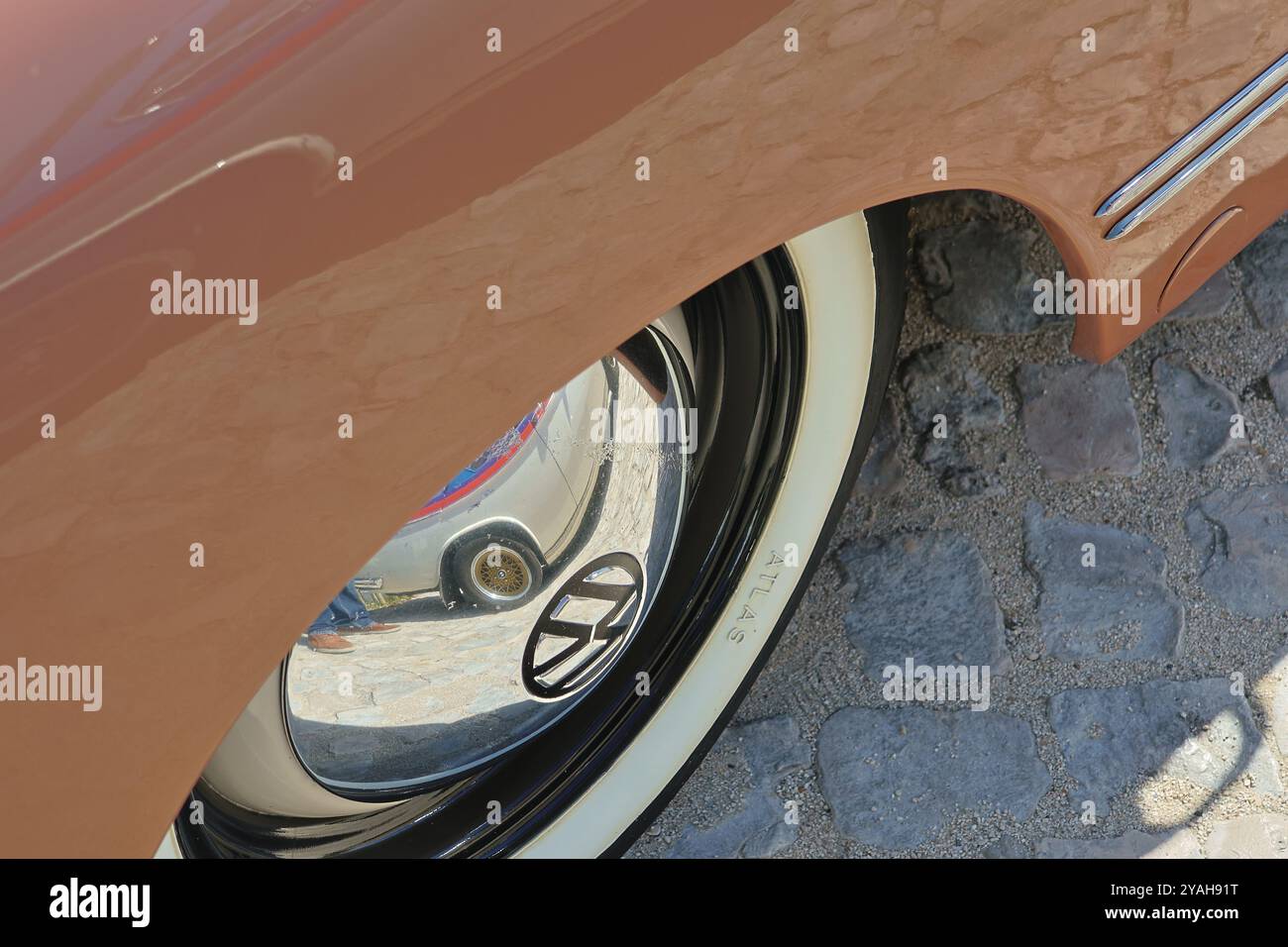 Chrome hubcap reflecting a white volkswagen karmann ghia parked on a ...