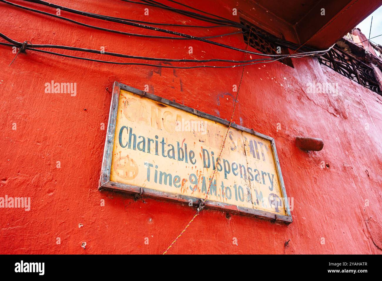 Sign on a wall for a charitable dispensary name and opening hours in ...