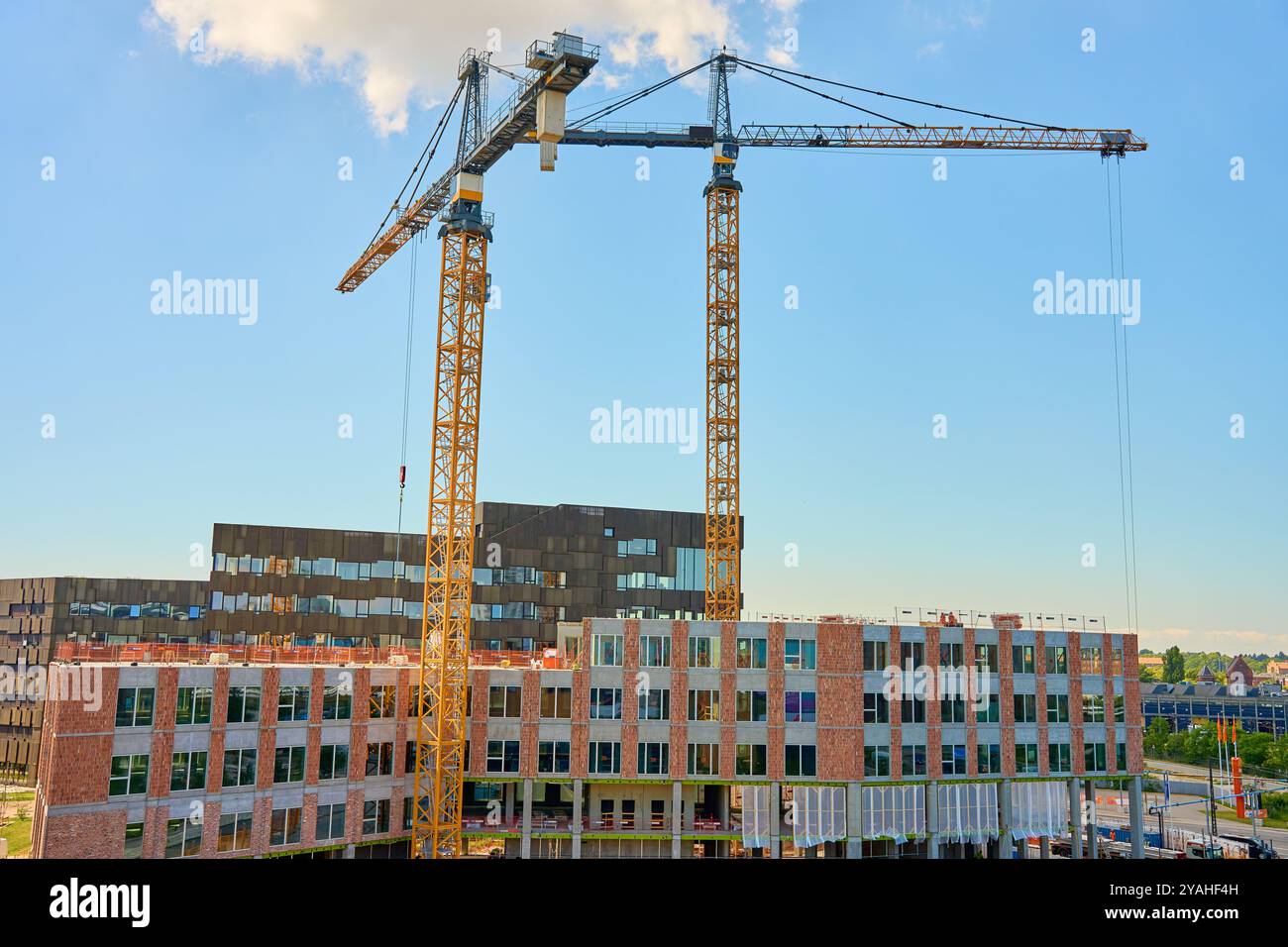Two large tower cranes at construction site against clear blue sky ...