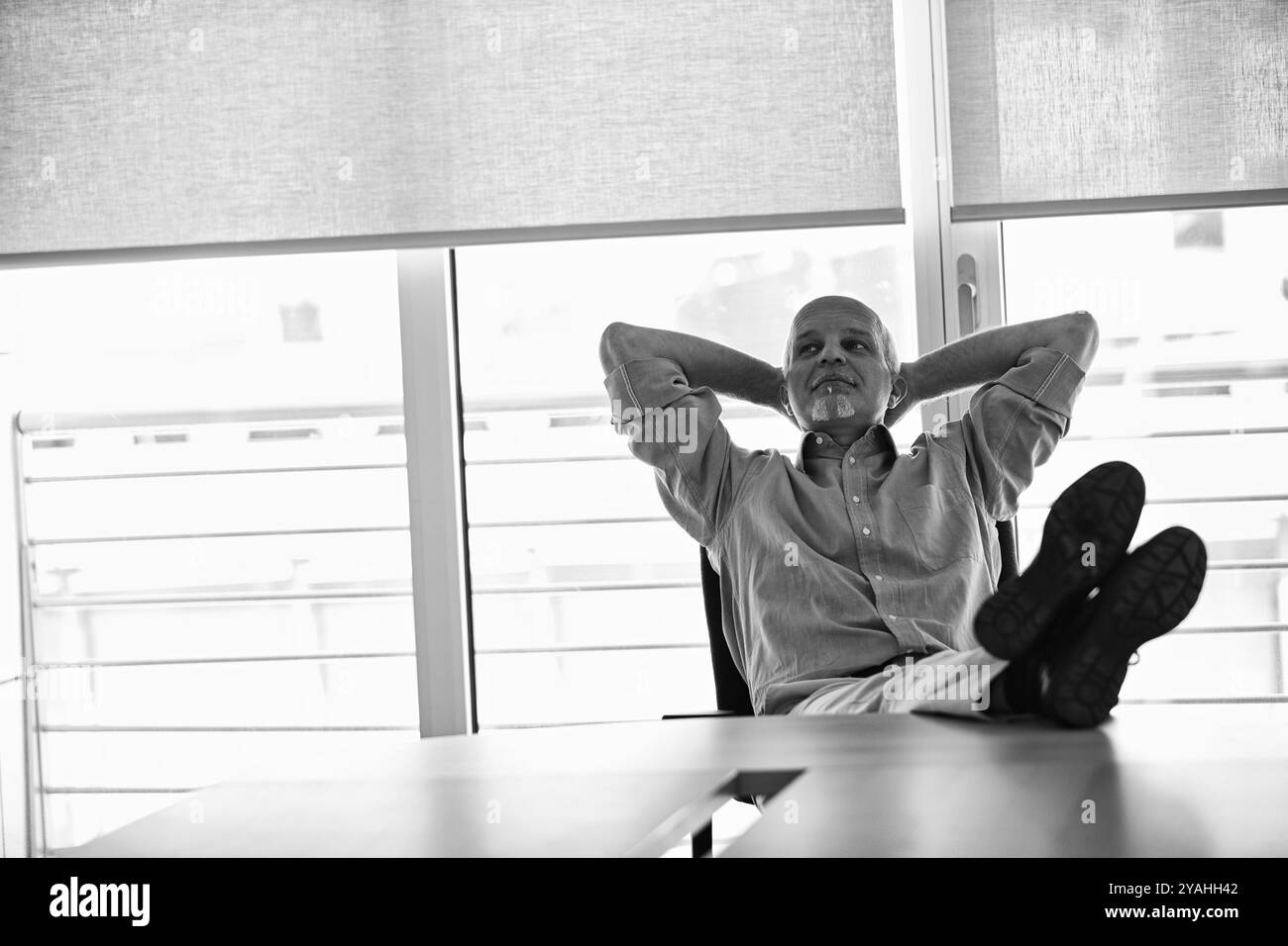 Mature businessman is taking a break from work, leaning back in his ...