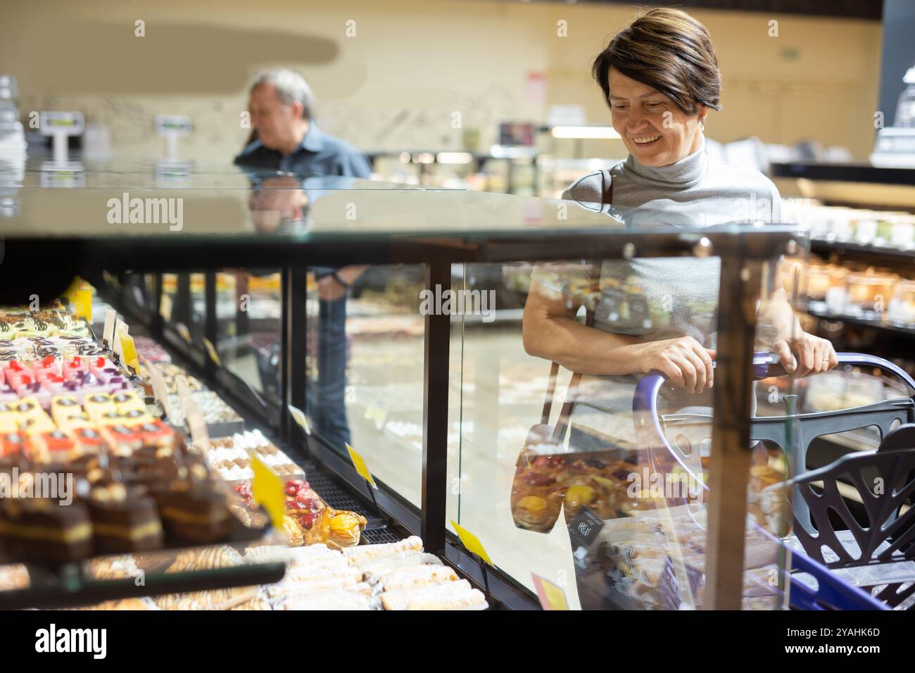 Woman chooses cakes at showcase of confectionery department Stock Photo ...