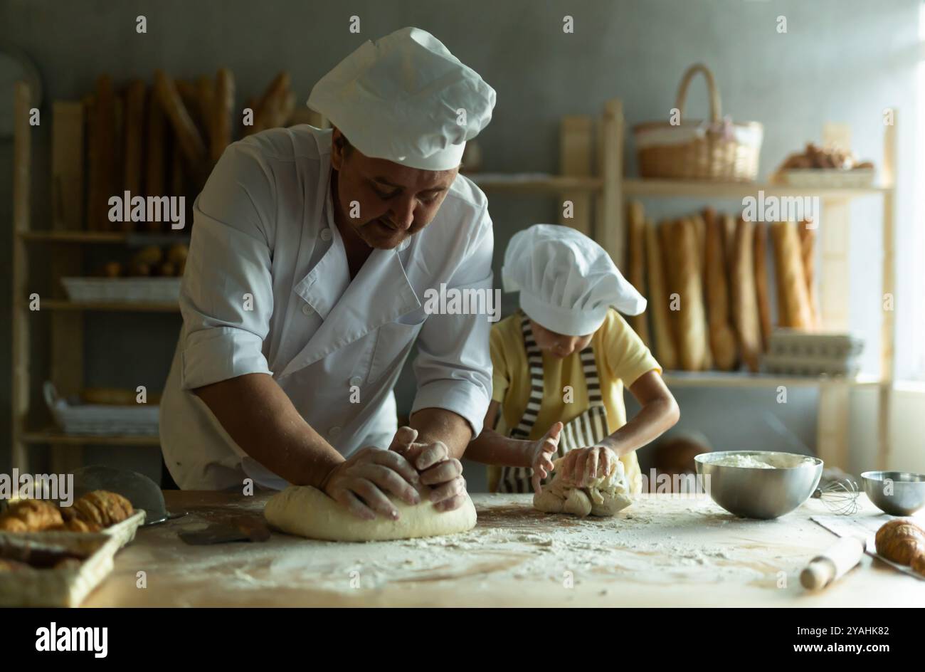 Little daughter and father make dough together in bakery kitchen Stock ...