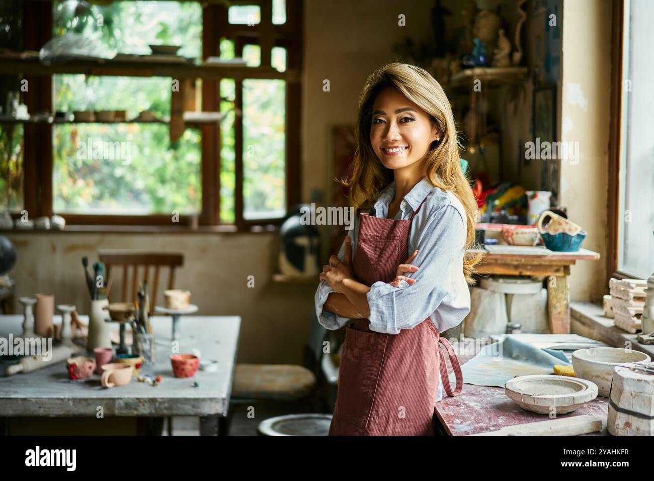 Pretty female artist smiling and posing at creative workshop with her ...