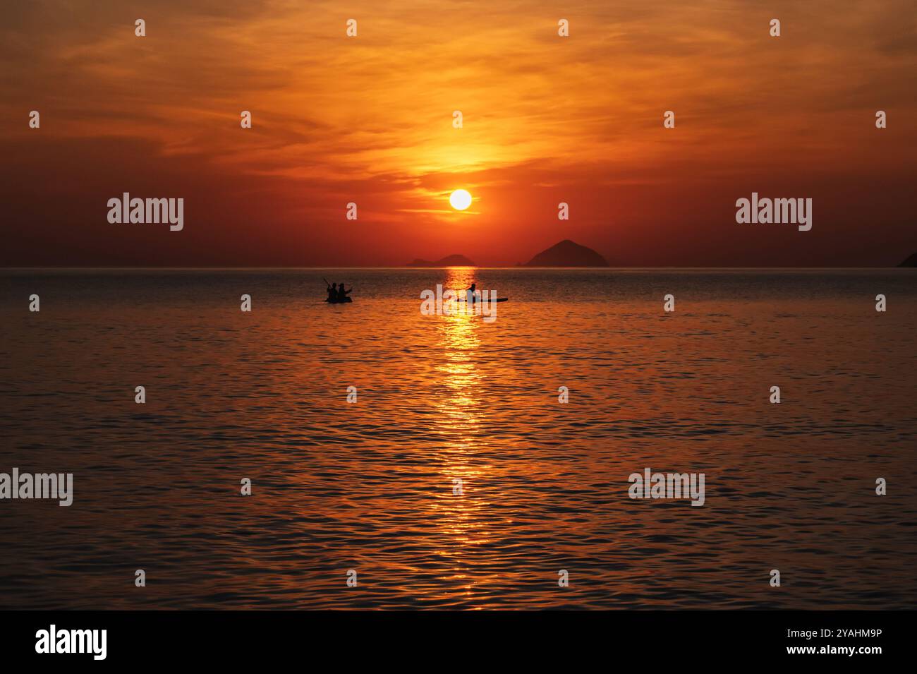 Silhouettes of people floating on sap boards in the sea in the evening ...