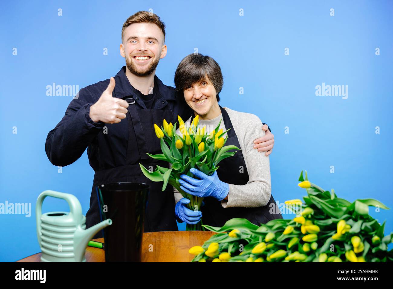 Flower shop. A young guy helps an older woman florist take care of ...