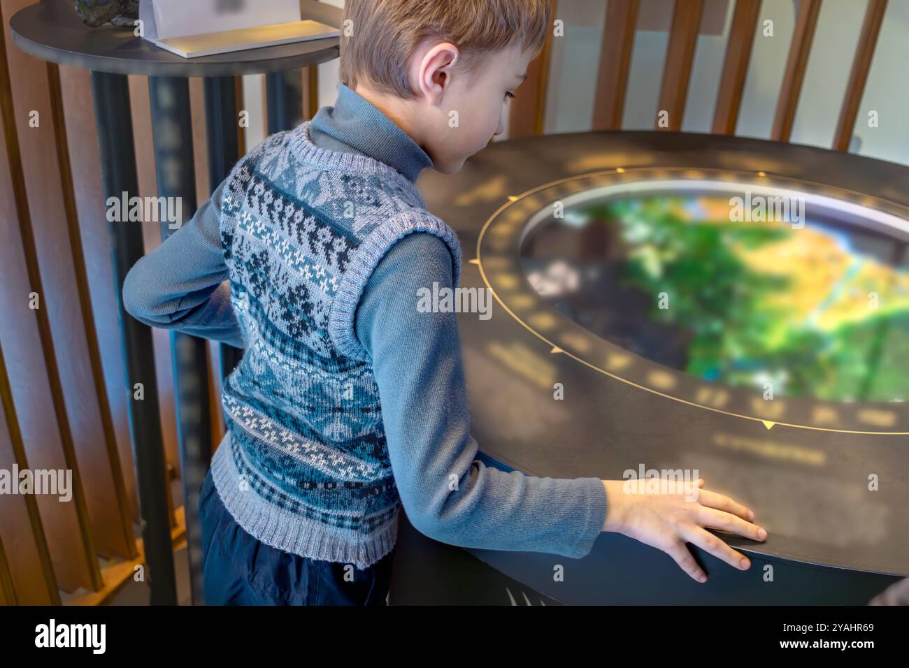 Boy interacts with a circular interactive screen at an exhibit. Like ...