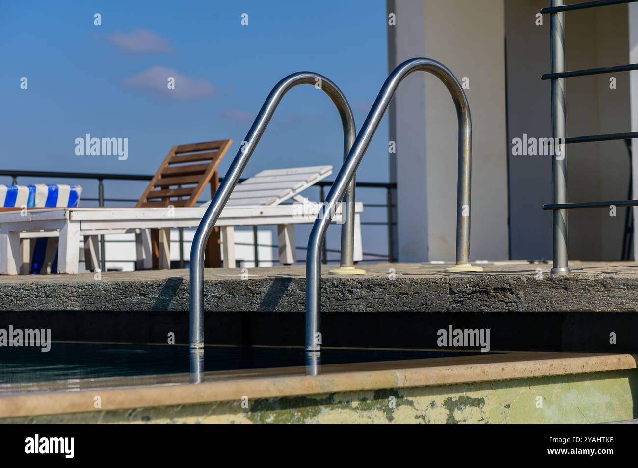 Steps into the pool with handrails in water reflex sun. For tourists ...