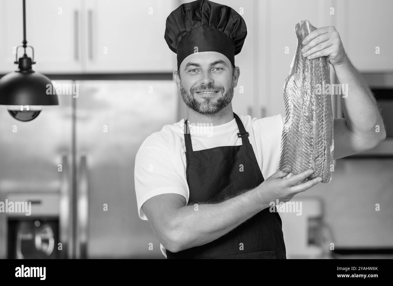 Chef in uniform cooking raw fish salmon fillet in the kitchen ...