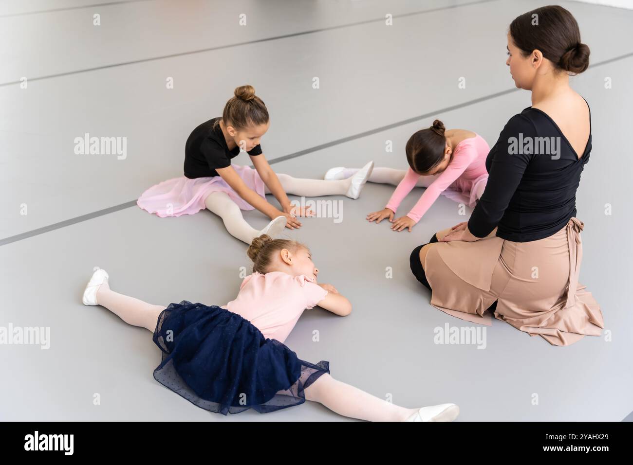 Pretty girls sitting on floor in ballet studio practicing stretching ...