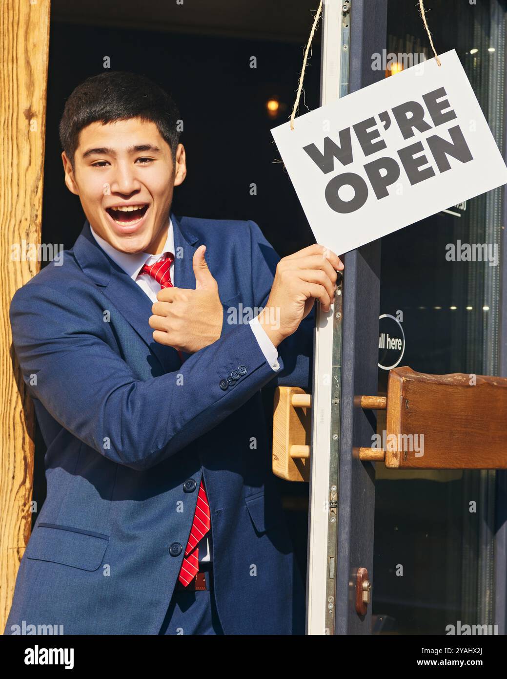 Positive and confident man in blue suit with we are open sign hanging ...