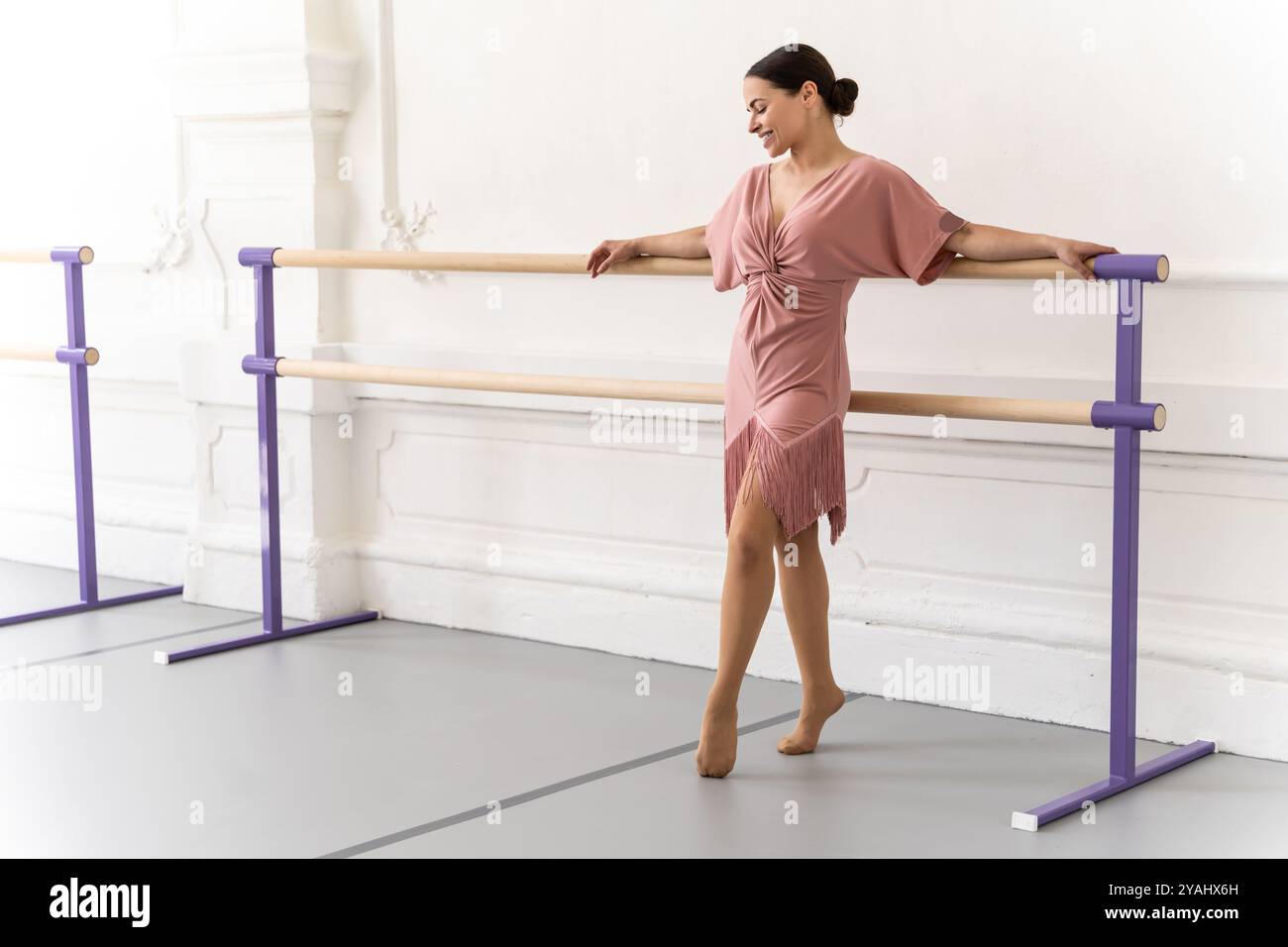 Beautiful woman practicing ballet at barre in studio wearing elegant ...