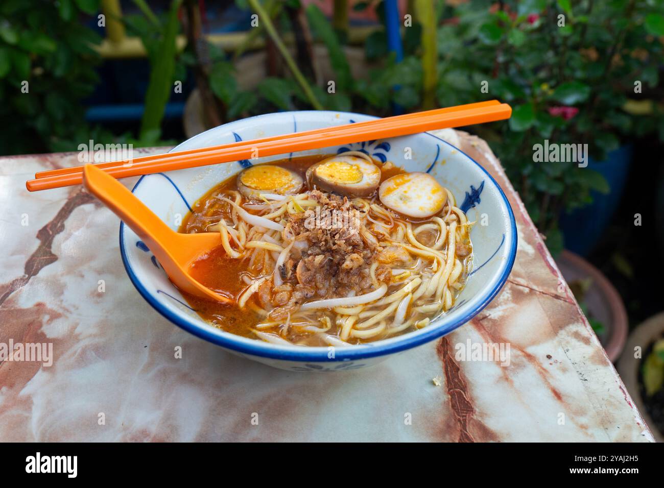 A bowl of hokkien noodle filled with anchovies, egg, bean sprouts in ...