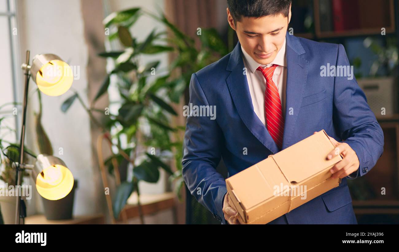 Man in formal wear, suit with red tie packing cardboard packages ...