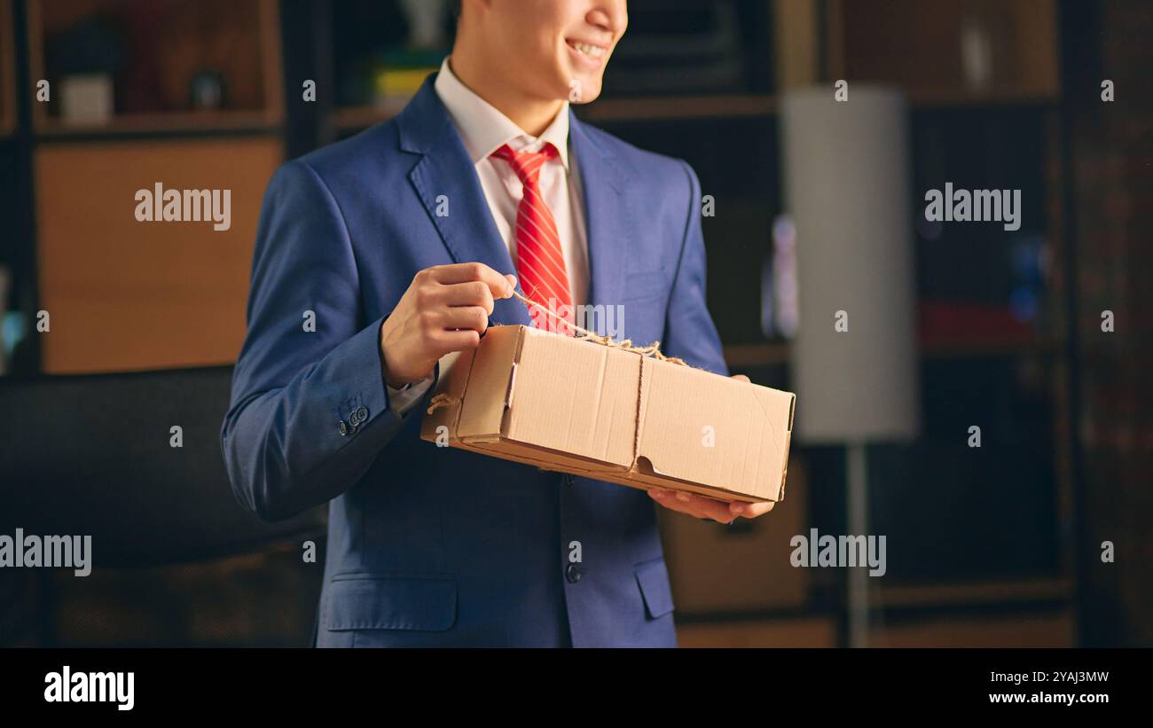 Cropped image of man in formal wear packing cardboard packages ...