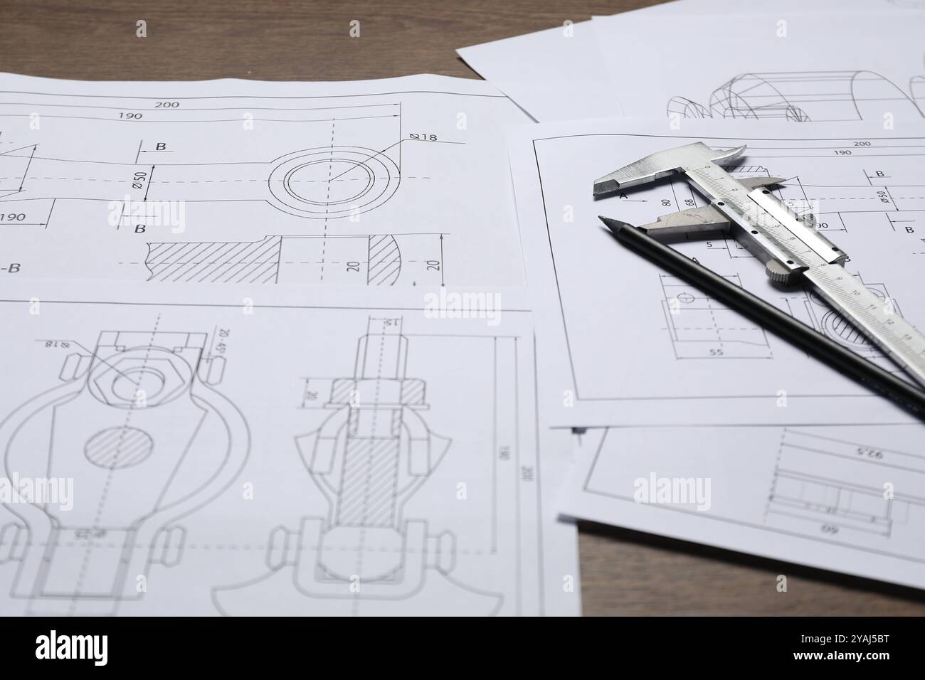 Different engineering drawings, vernier caliper and pencil on table ...