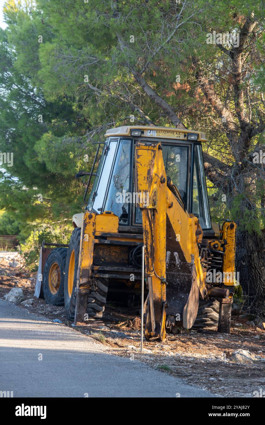 large yellow JCB parked at the side of a road under some trees Stock ...