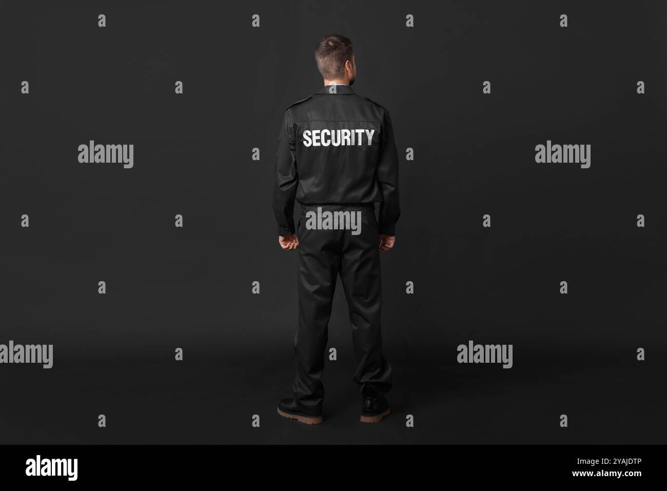 Security guard in uniform on black background, back view Stock Photo ...