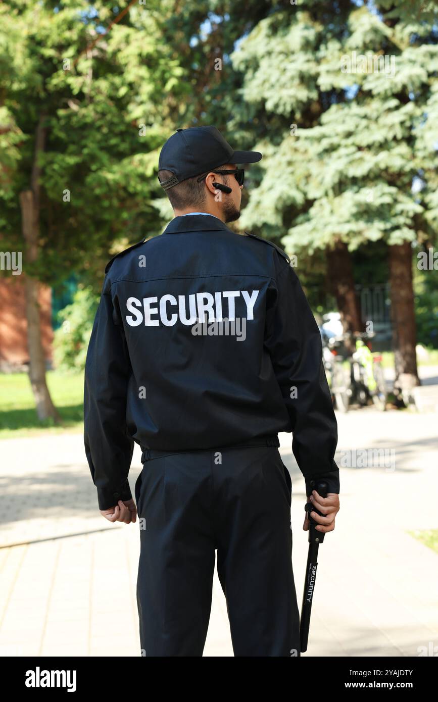 Security guard in uniform with baton outdoors, back view Stock Photo ...